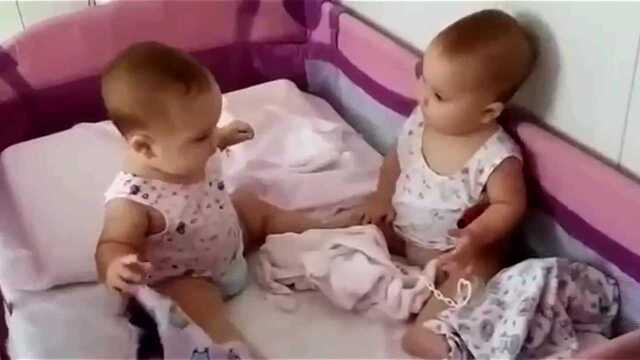 Twin baby sitting in the crib facing the face and smirking, so cute ...